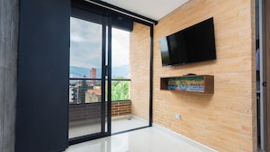Quarto moderno com uma grande porta de vidro deslizante, televisão de tela plana fixada em uma parede de tijolos e uma pequena prateleira com uma bicicleta e uma placa.