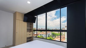 Quarto com uma janela grande, uma cama e um guarda-roupa embutido.