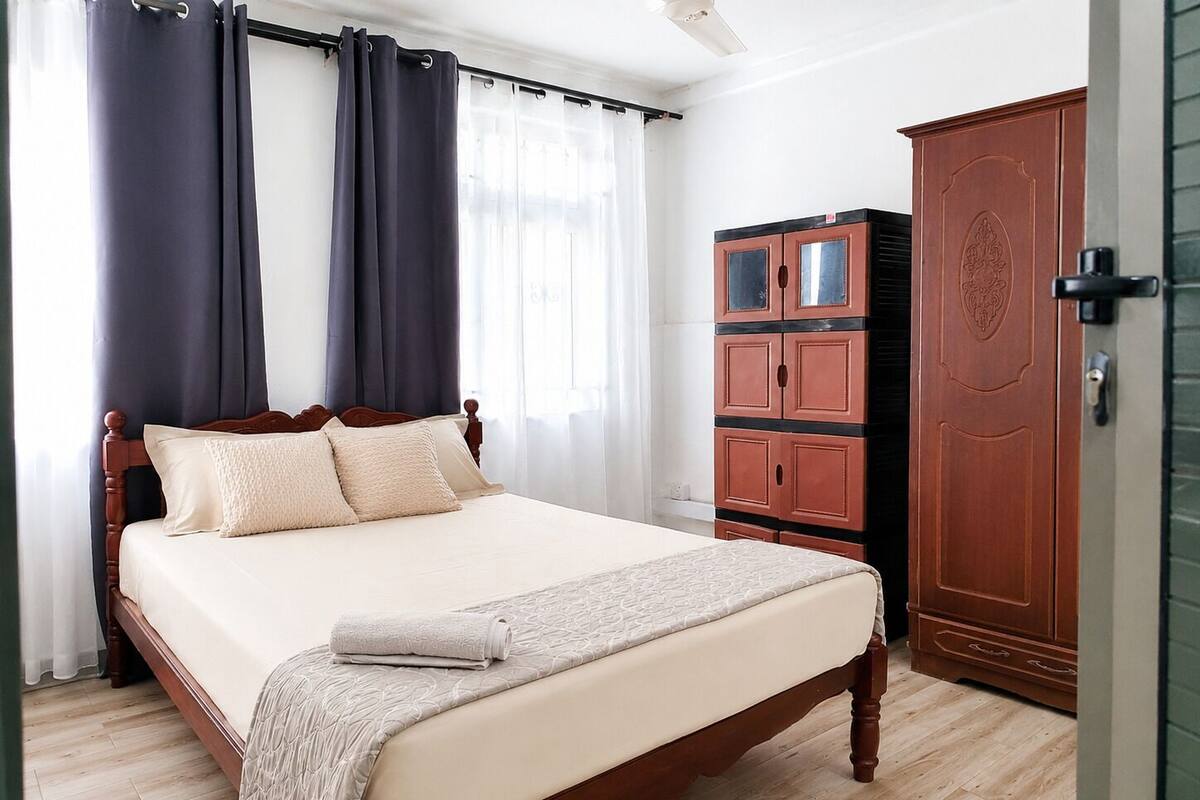 Quarto com cama de madeira, guarda-roupa e uma porta.