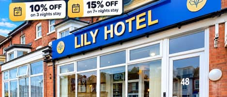Hotel chamado 'Lily Hotel', com placa oferecendo descontos para estadias prolongadas.