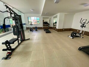 Uma academia com diversos equipamentos de exercício, incluindo esteira, bicicleta ergométrica e aparelhos de musculação.