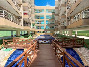 Um hotel com vários níveis, piscina central, área de estar externa e galeria coberta.