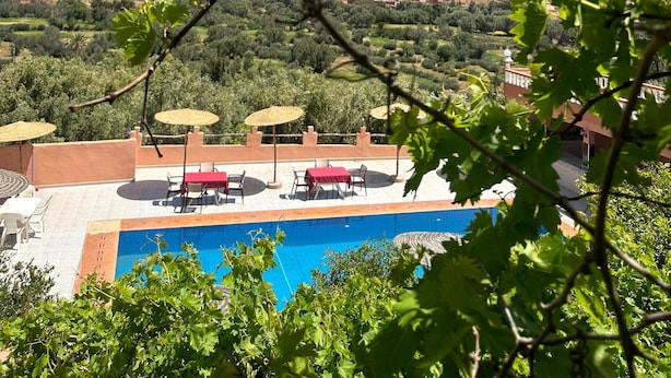 Uma área de piscina com mobiliário ao ar livre e vista para uma paisagem montanhosa.