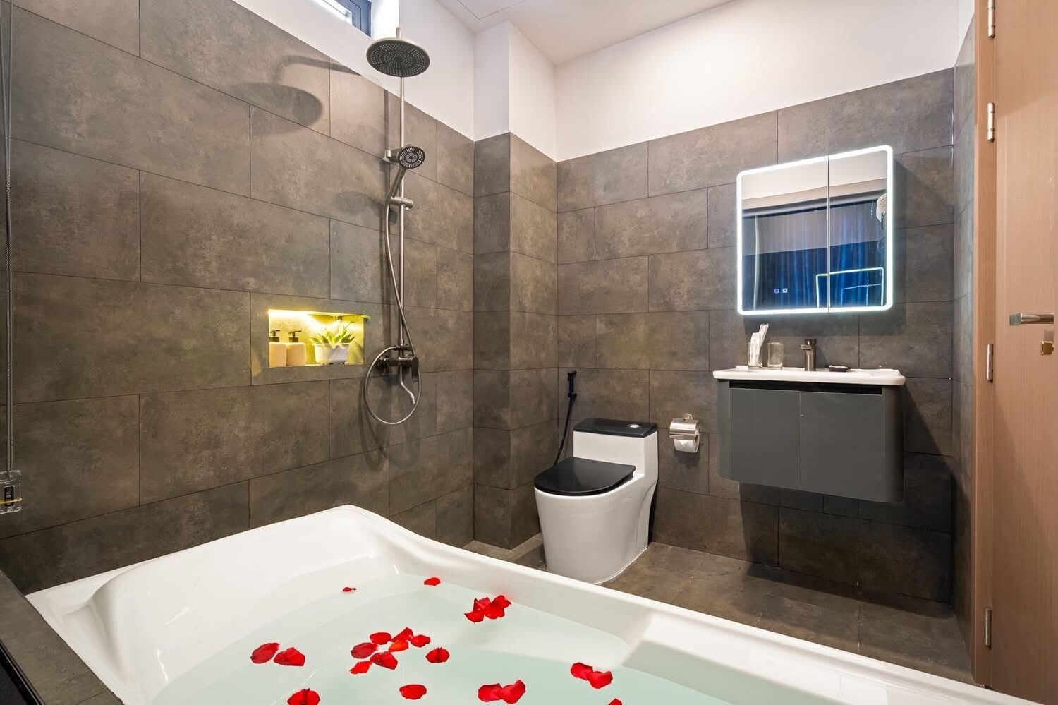 Uma casa de banho moderna com banheira, chuveiro, sanita e lavatório.