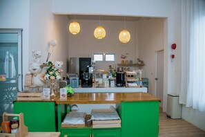 Cozinha com bancada de madeira, armários verdes e luminárias pendentes, além de diversos eletrodomésticos.