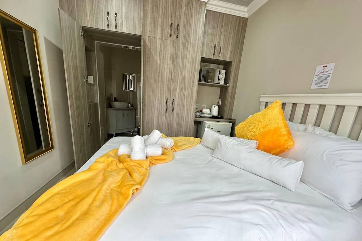 Quarto de hotel com cama, guarda-roupa, mesa de cabeceira e espelho.