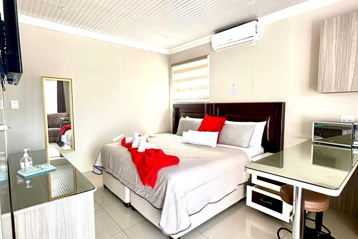Quarto de hotel moderno com cama, mesa de cabeceira, escrivaninha e televisão de tela plana.