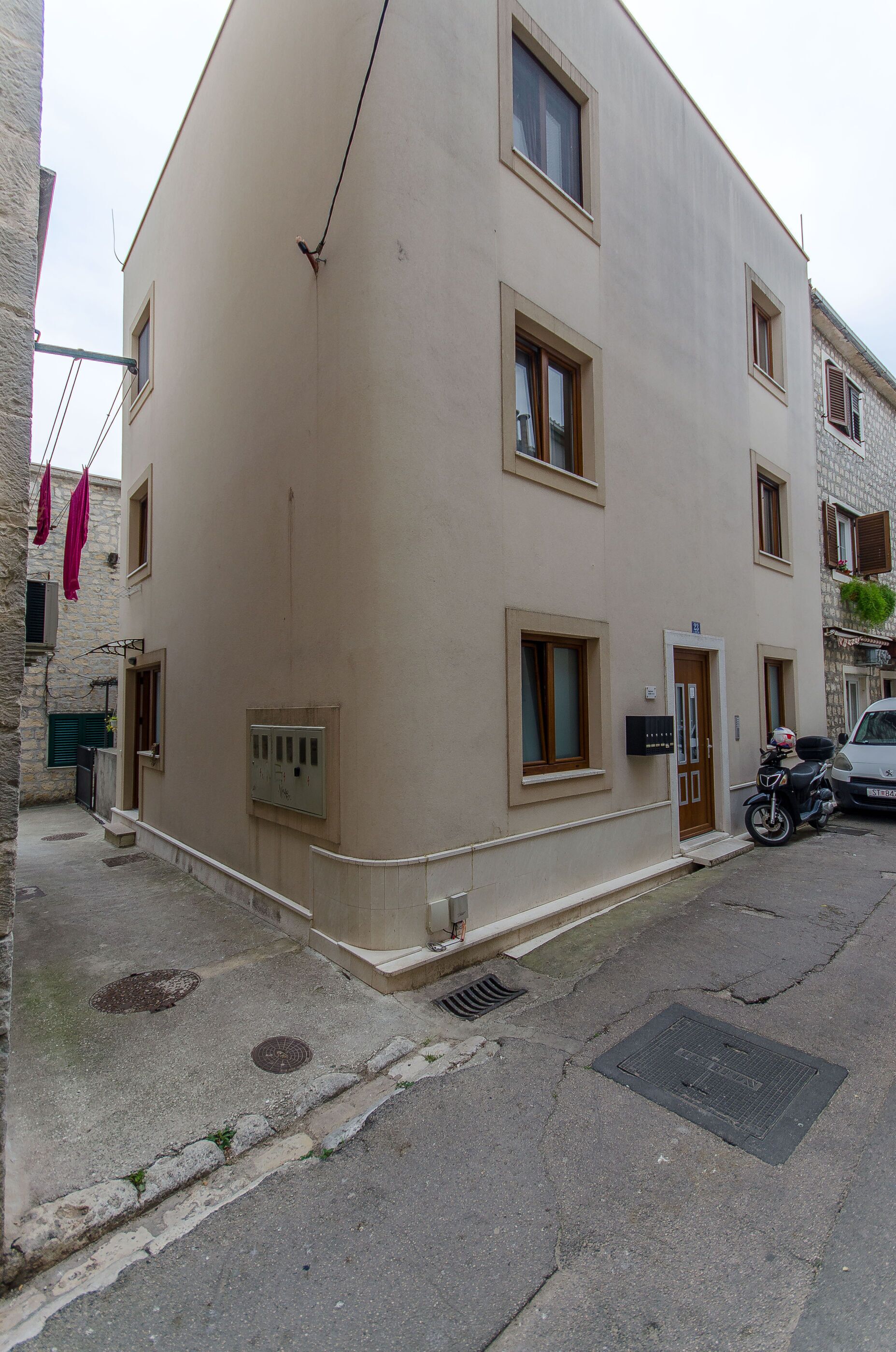 Um edifício de vários andares com fachada bege, várias janelas, uma porta com um letreiro e uma motocicleta estacionada na frente.