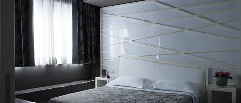 Um quarto moderno com uma cama, mesas de cabeceira e uma janela com cortinas.