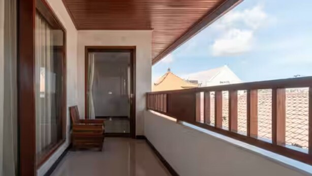 Um corredor com teto de madeira, janelas amplas e vista para edifícios do lado de fora.