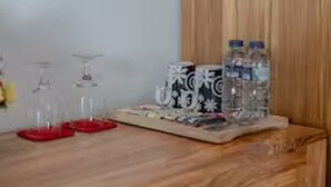 Uma mesa de madeira com uma bandeja contendo uma garrafa de água, uma caneca e um copo.
