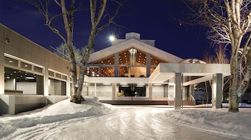 Um edifício moderno com uma entrada ampla, diversas janelas e chão coberto de neve.