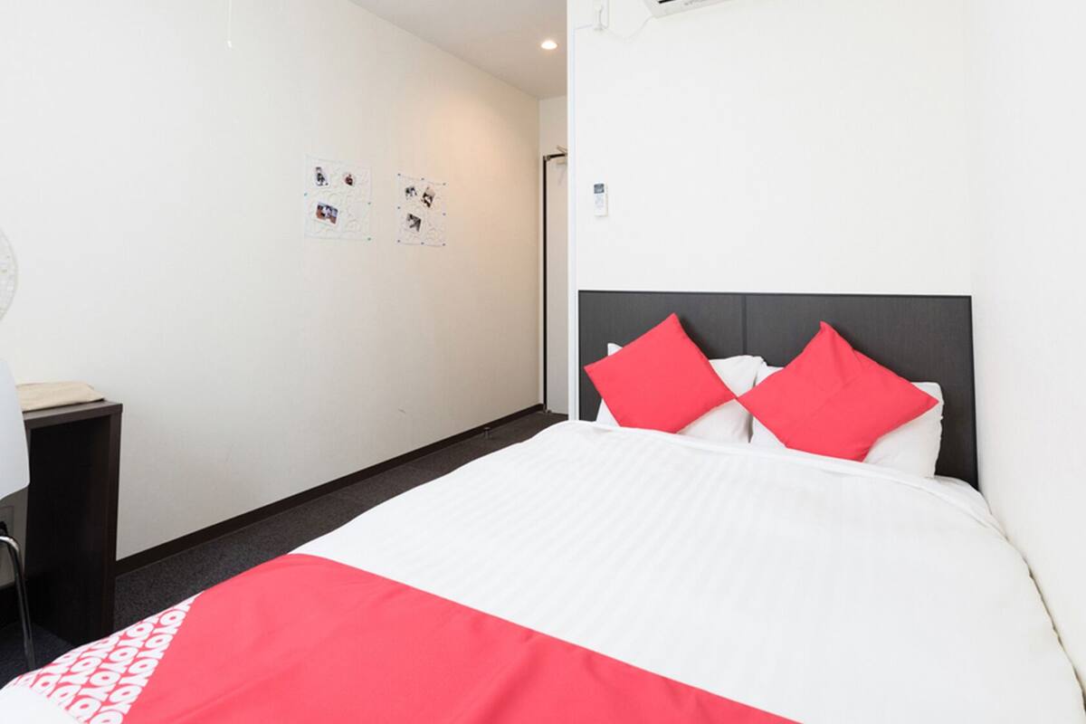Quarto de hotel com uma cama, uma mesa de cabeceira, um espelho e uma parede com fotografias.