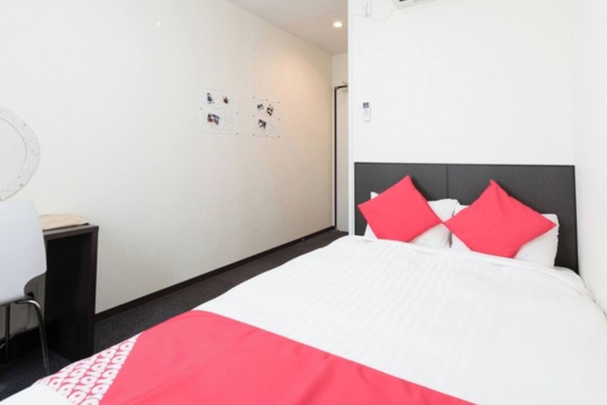 Quarto de hotel com cama, mesa de cabeceira e um painel na parede com um mural.