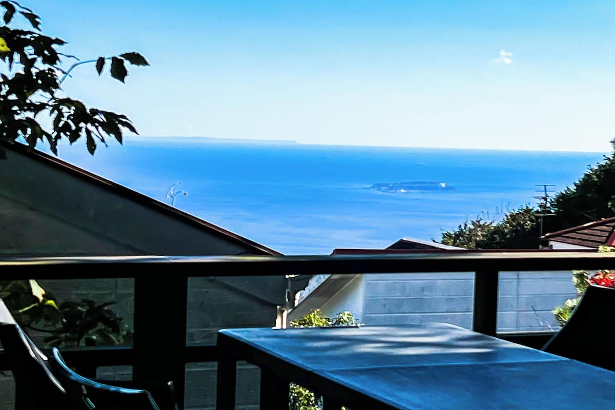 Uma varanda com vista para o mar, uma mesa e uma cadeira.