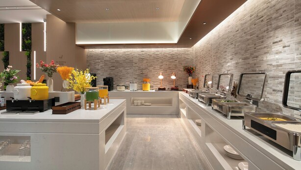 Uma moderna disposição de buffet com várias estações de comida, parede de tijolos e iluminação contemporânea.