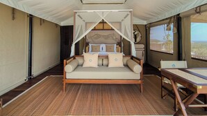 Quarto com tenda, cama, ventilador de teto e vista para o exterior.