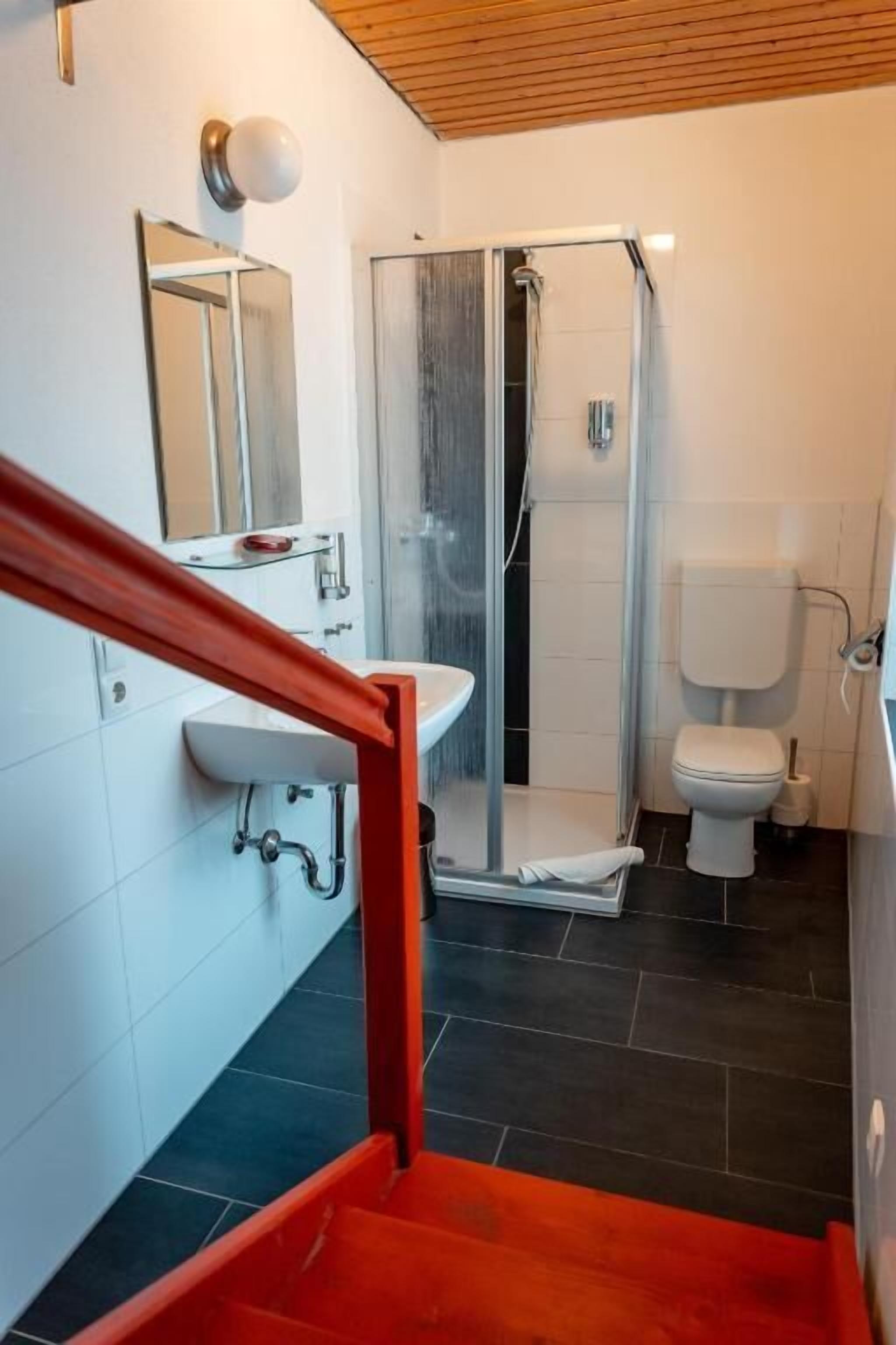 Uma casa de banho moderna com chuveiro, sanita e lavatório.