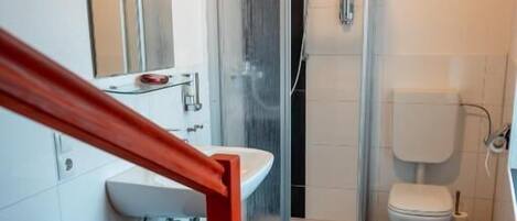Uma casa de banho moderna com chuveiro, sanita e lavatório.