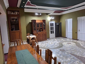 Uma sala de jantar com mesa de madeira, cadeiras, um armário e piso estampado.