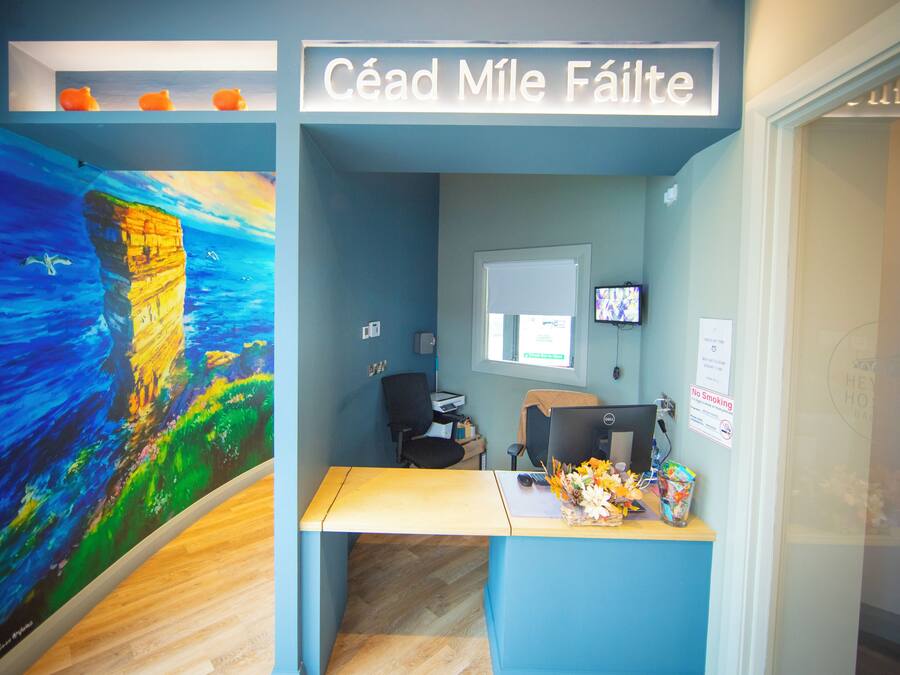 Uma receção com um computador, um monitor e um letreiro que diz 'Céad MILE Fáilte'.