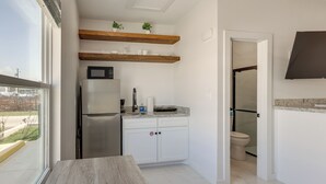 Cozinha moderna com frigorífico, micro-ondas e prateleiras de madeira acima do balcão.