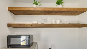 Cozinha com micro-ondas, prateleiras de madeira e plantas em vasos.