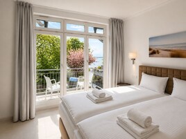 Quarto de hotel com uma cama grande, vista para o exterior e varanda com cadeiras.