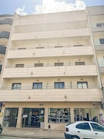 Um hotel de vários andares com fachada plana, grandes janelas e uma loja no térreo.