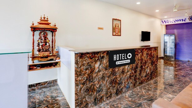 Balcão de recepção de hotel com bancada de mármore, um pequeno santuário e um letreiro com a palavra 'Welcome'.