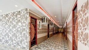 Um corredor com paredes padronizadas, unidades de ar condicionado e piso de azulejos.