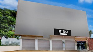 Hotel com um grande letreiro, persianas fechadas e uma placa indicando ser um hotel de serviço corporativo.