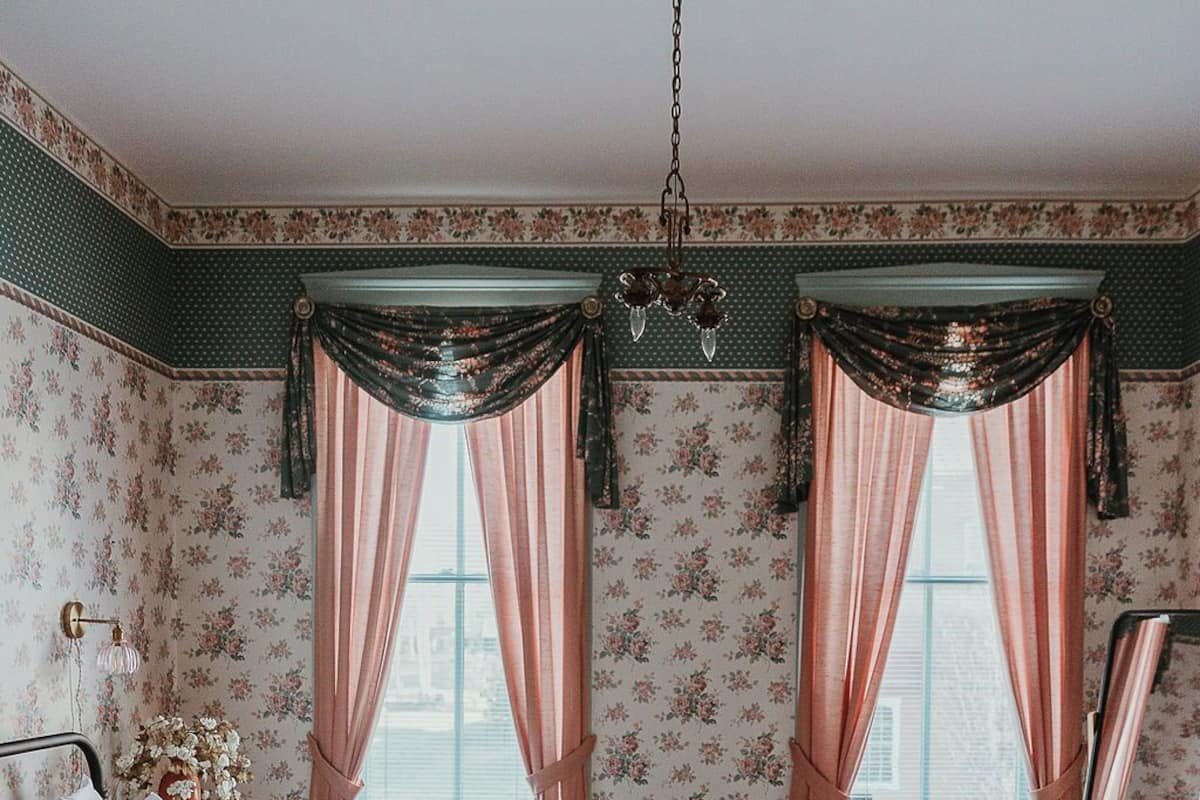 Quarto com cama, um banco, uma cadeira, cômoda e espelho.