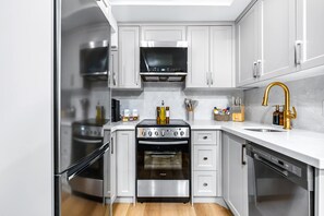 Uma cozinha moderna com eletrodomésticos de aço inoxidável, armários brancos e uma torneira dourada.