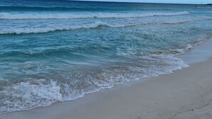 Uma praia com ondas, céu claro e horizonte distante.
