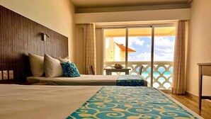 Quarto de hotel com uma cama grande, varanda com vista e uma pequena mesa.