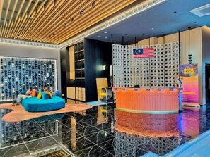Um lobby moderno com um sofá azul, um balcão de recepção e uma parede decorativa com uma bandeira.