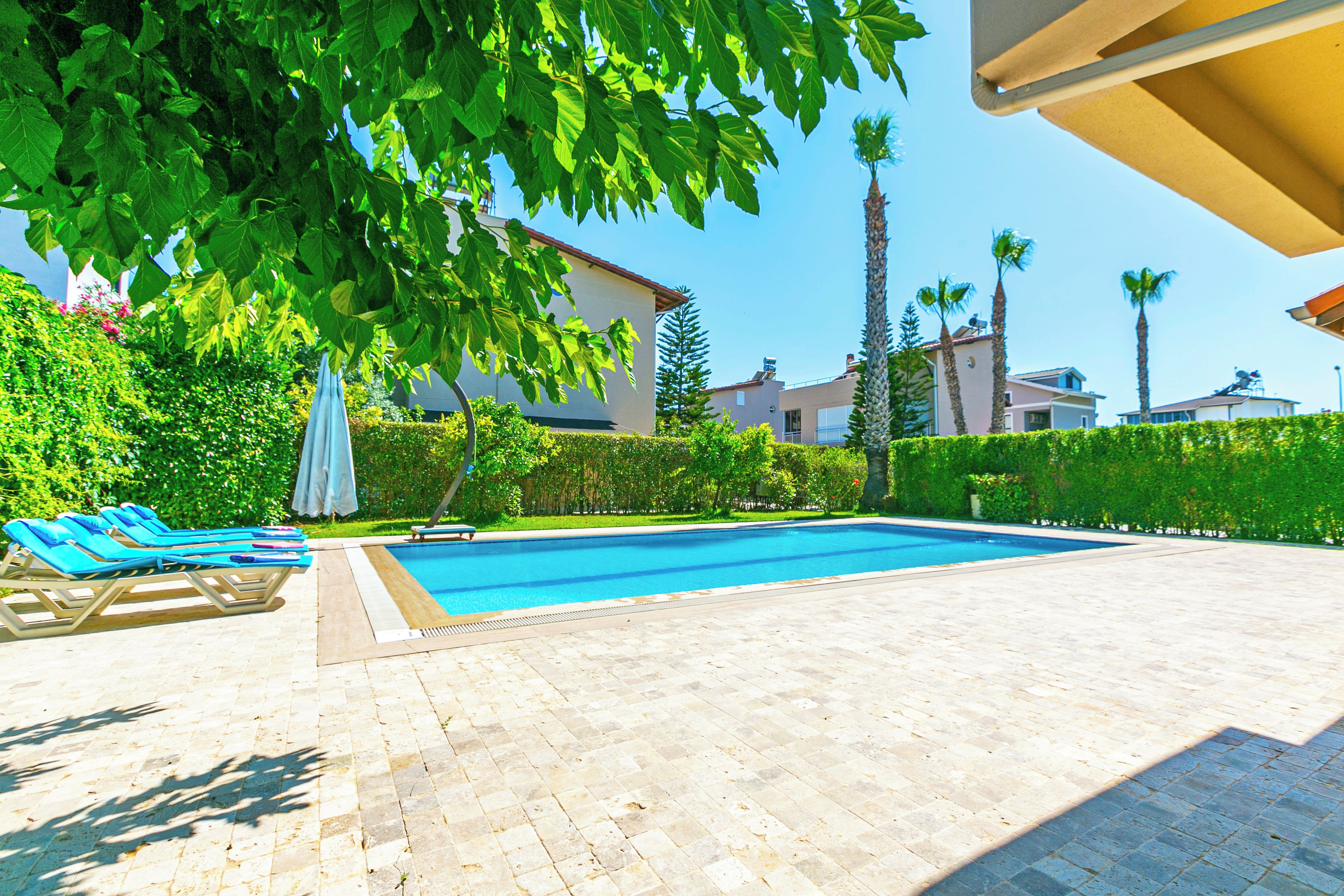 Piscina com espreguiçadeiras e pérgola.