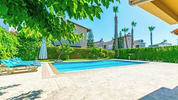 Piscina com espreguiçadeiras e pérgola.