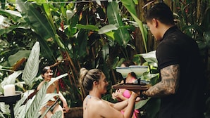 Cenário tropical com piscina rodeada por vegetação exuberante e plantas grandes.