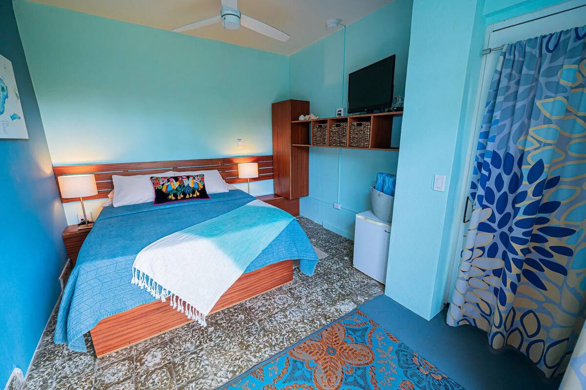 Quarto com cama, mesas de cabeceira, televisão e guarda-roupa.