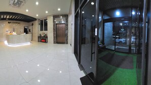 Uma área de recepção de hotel com balcão, lareira e elevador.