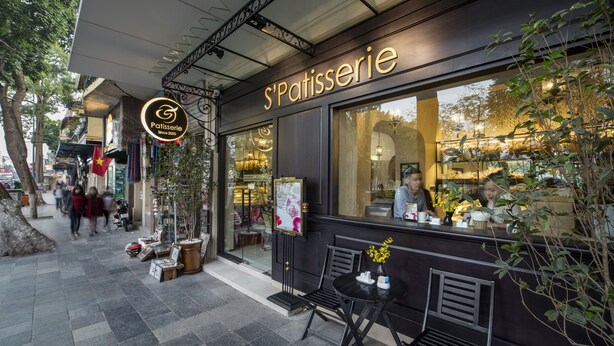 Vitrine com uma placa indicando "S'Patisserie" e uma exposição de produtos de panificação no exterior.