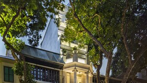 Um edifício histórico com uma varanda imponente, um café e uma placa com 'Silk Boutique'.