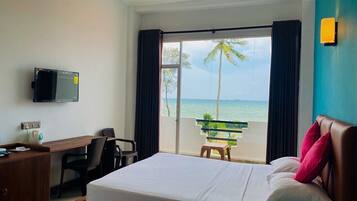 Quarto de hotel com cama, escrivaninha, cadeira e televisão na parede.