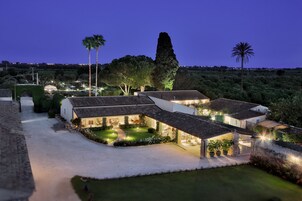 Uma vila com um pátio amplo, um jardim bem cuidado e vista para a paisagem ao redor.