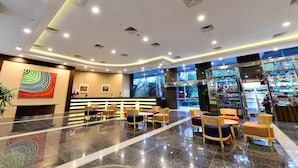 Um hall de hotel com balcão de recepção, área de estar e exposição de produtos.