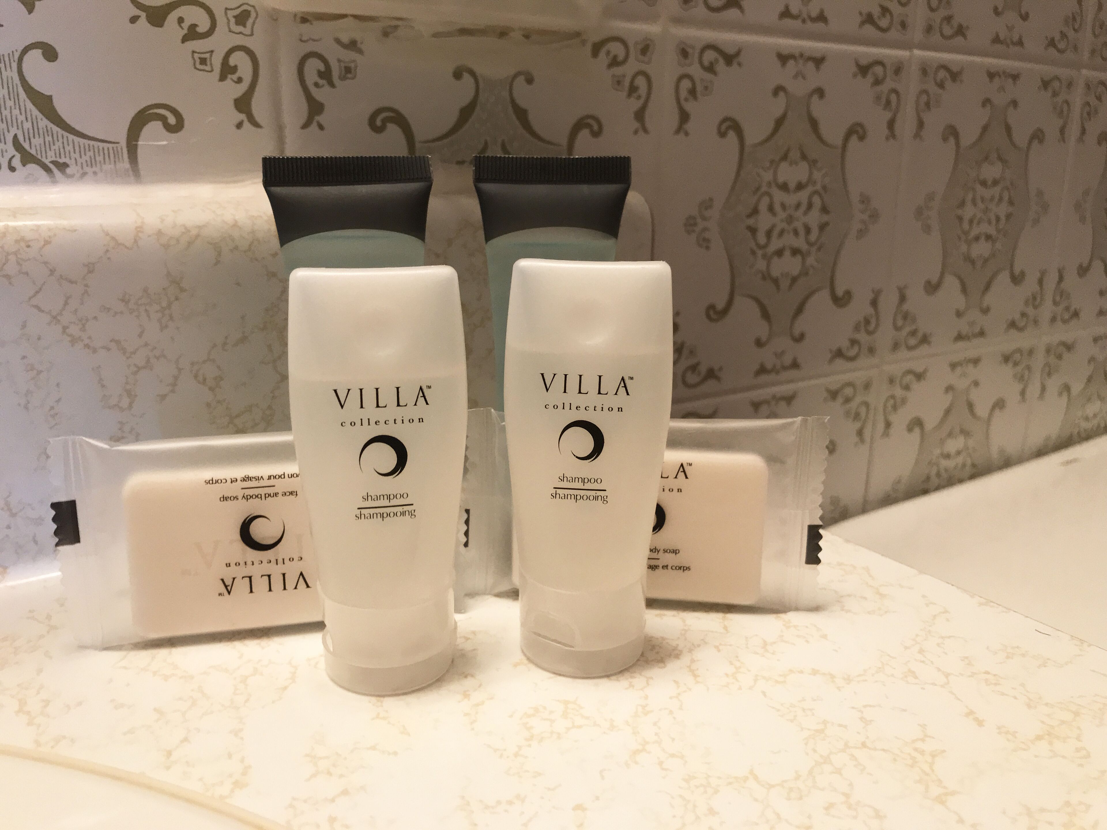 Duas garrafas de shampoo e condicionador Villa Collection em uma bancada de banheiro.