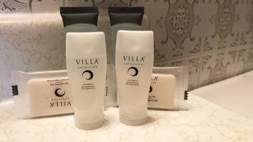 Duas garrafas de shampoo e condicionador Villa Collection em uma bancada de banheiro.
