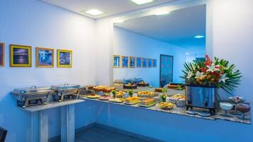 Buffet montado com diversos alimentos e um espelho grande refletindo o espaço.